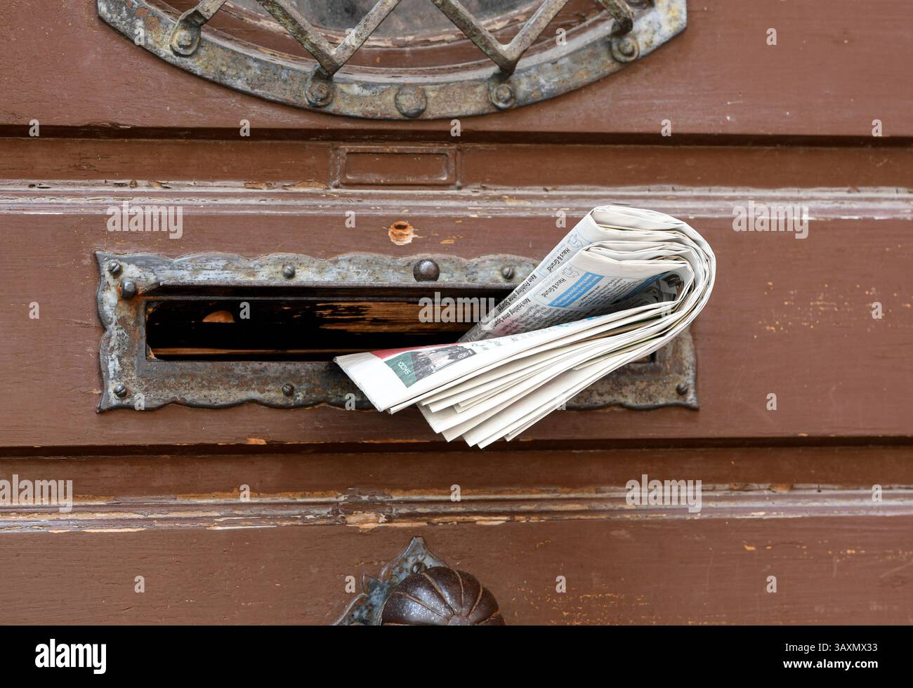 Alte Haustuer in Freiburg mit Briefschlitz und eingesteckter Zeitung ...