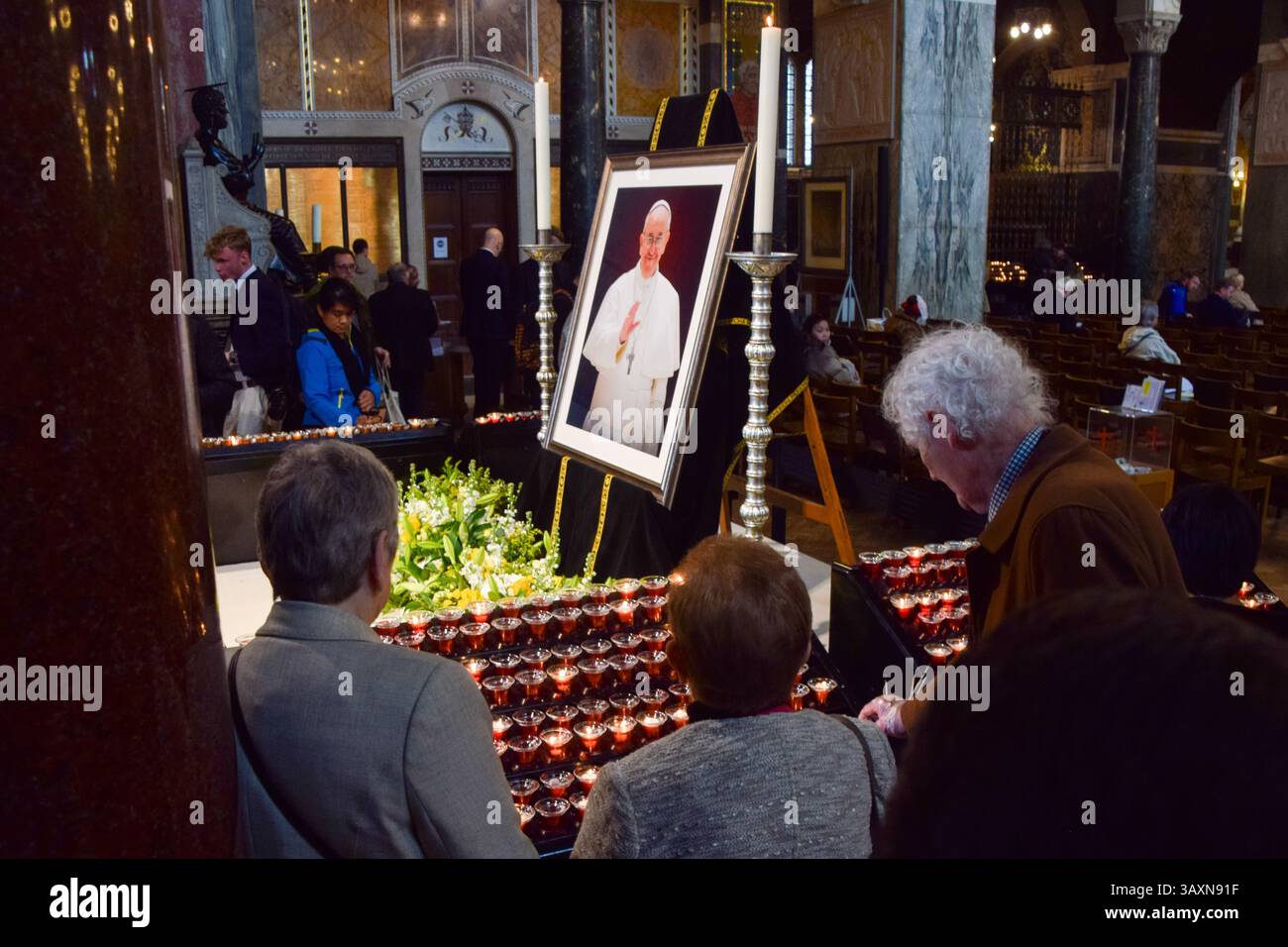 London, UK. 21st Apr, 2025. People light candles next to a picture of ...