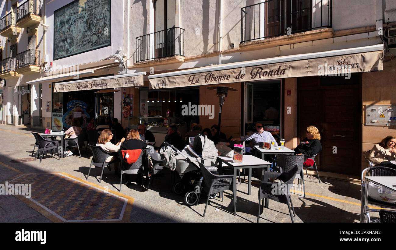 Tourists and locals relaxing at sidewalk cafe in Ronda, Spain, enjoying ...