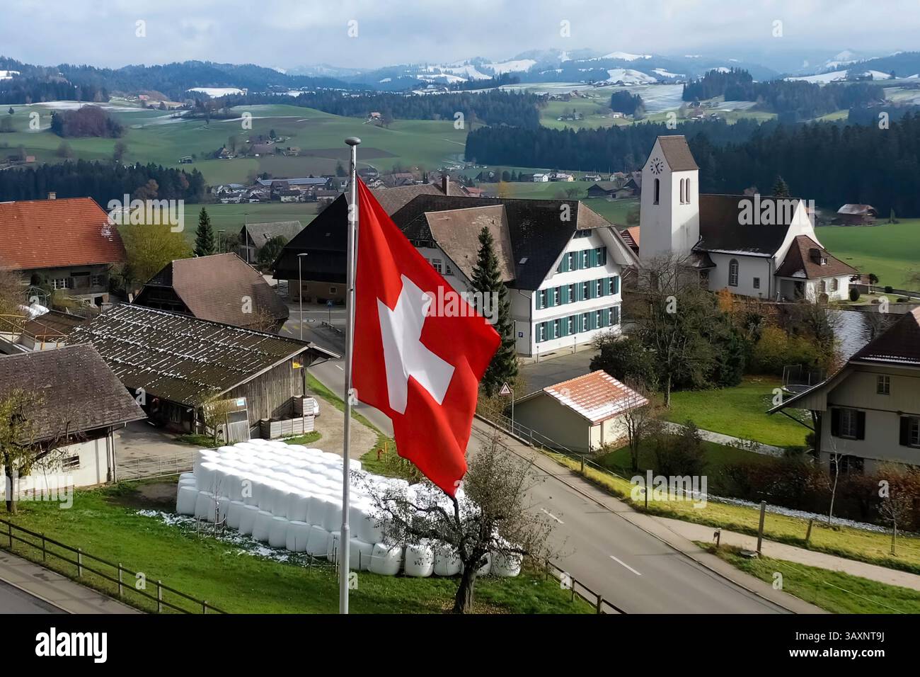 Swiss village, houses among the hills. Swiss flag against the ...