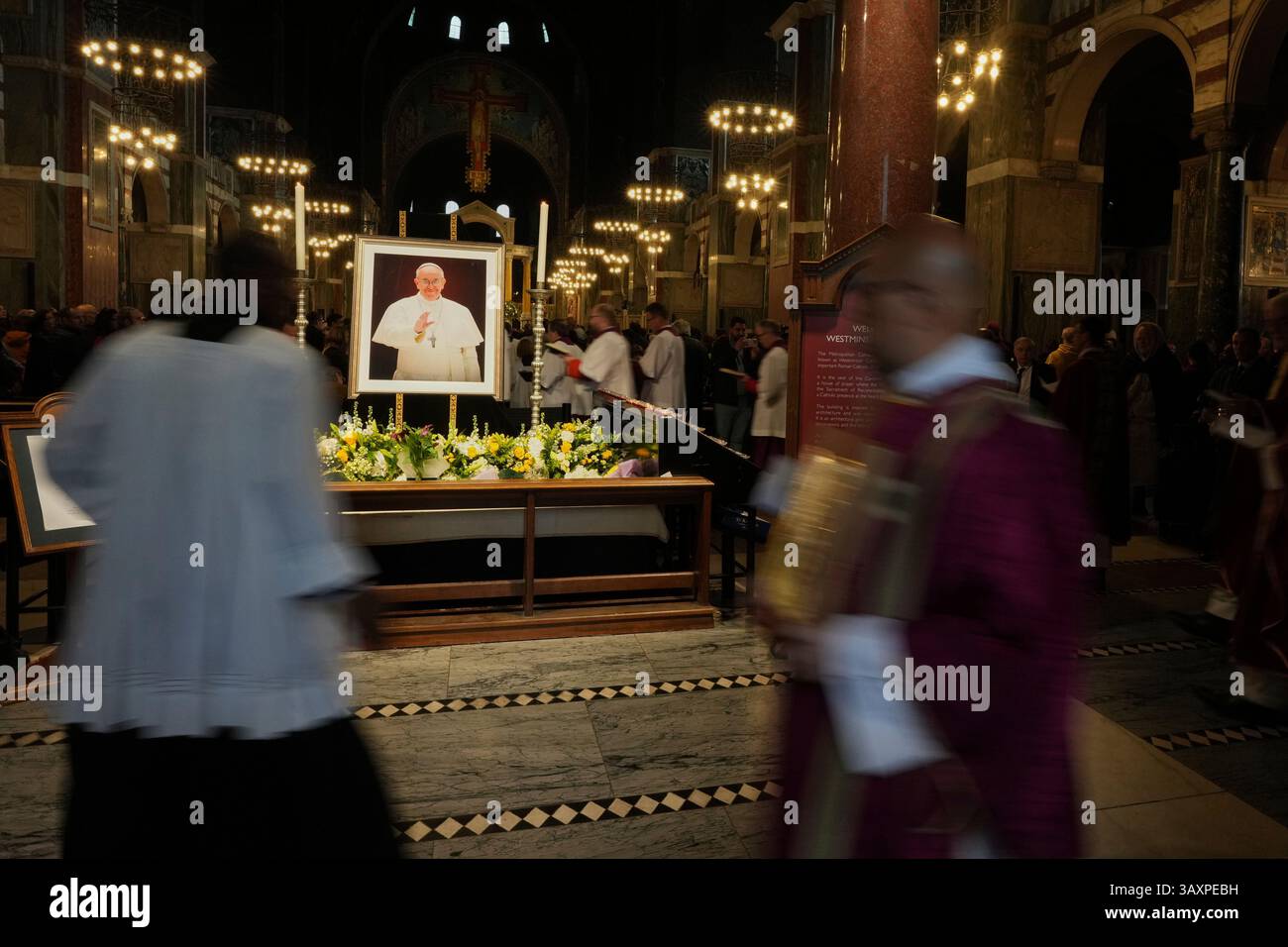 Members of the clergy in the procession pass by a photograph of Pope ...