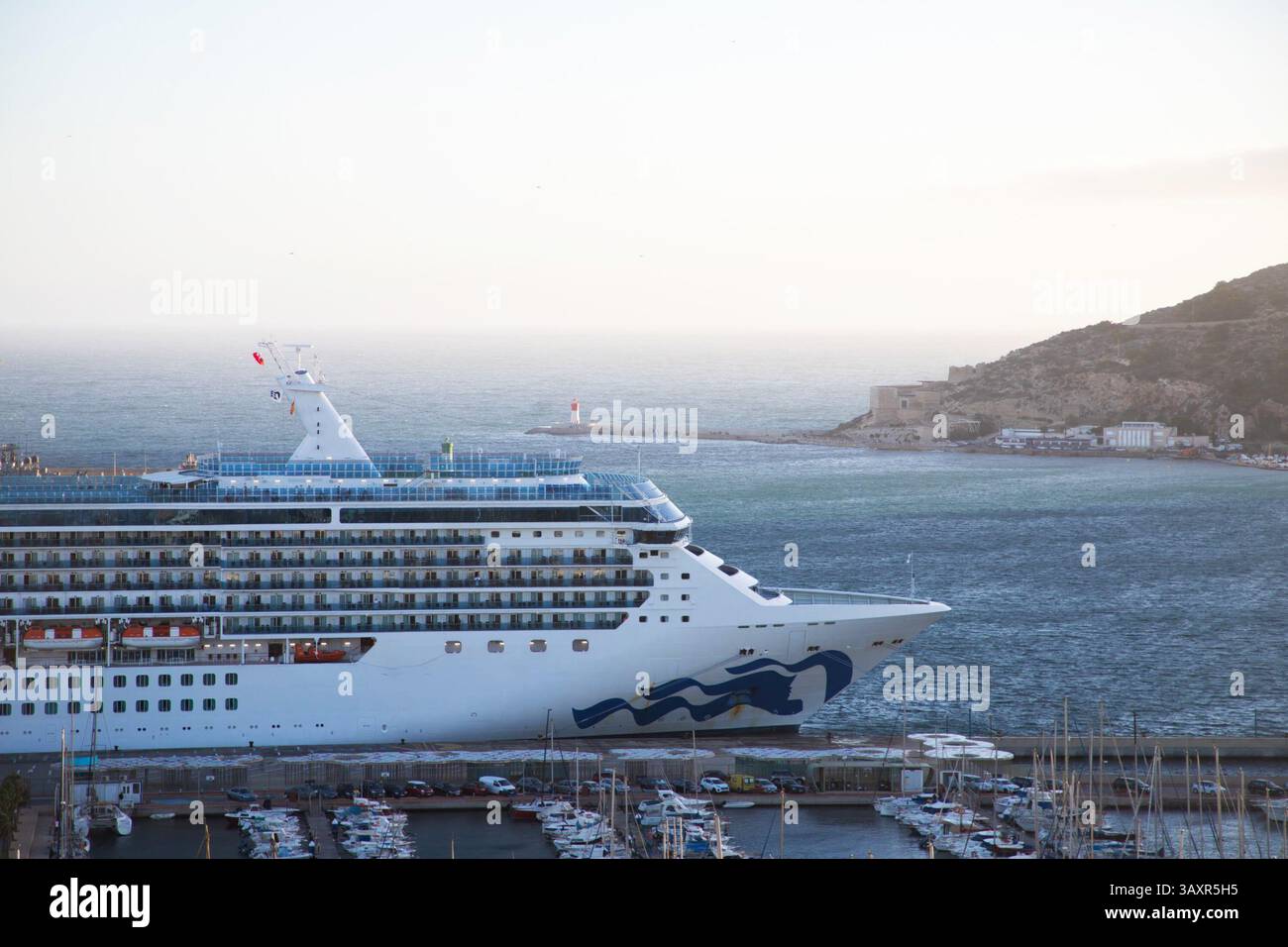 Cruise ship docked at port with oceanic horizon and scenic coastline in ...