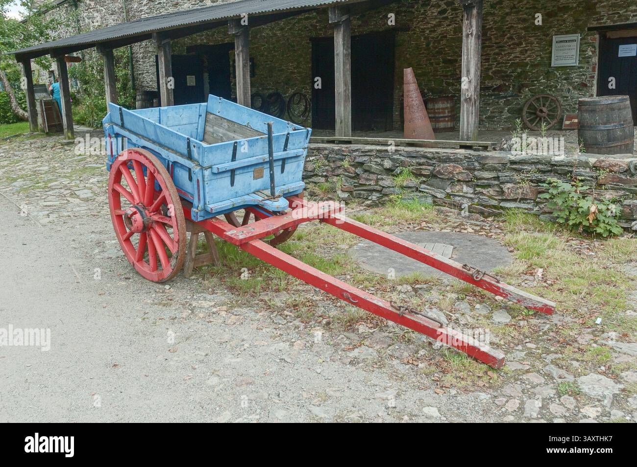 A blue and red 2-wheeled horse-drawn wooden cart at Morwellham Quay ...