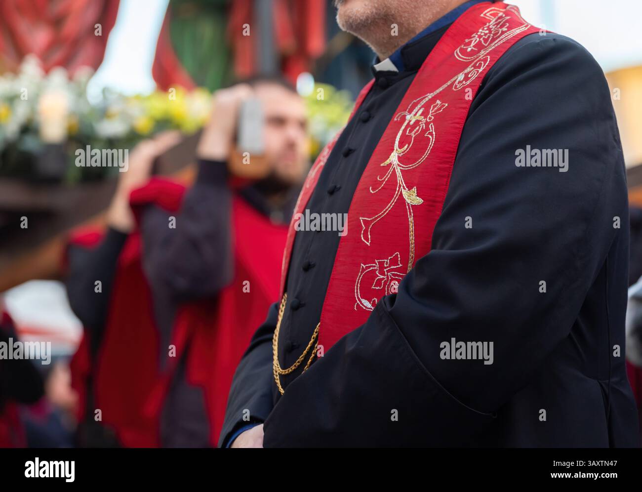 Catholic priest wearing a red stole with golden embroidery and a golden ...