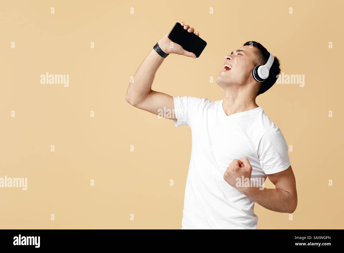 Cool young man in wireless headphones singing karaoke Stock Photo - Alamy
