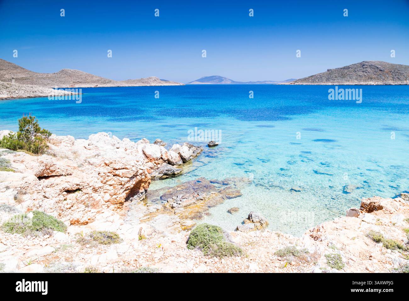 The azure sea meets the rocks and sand on the island of Chalki, Greece ...