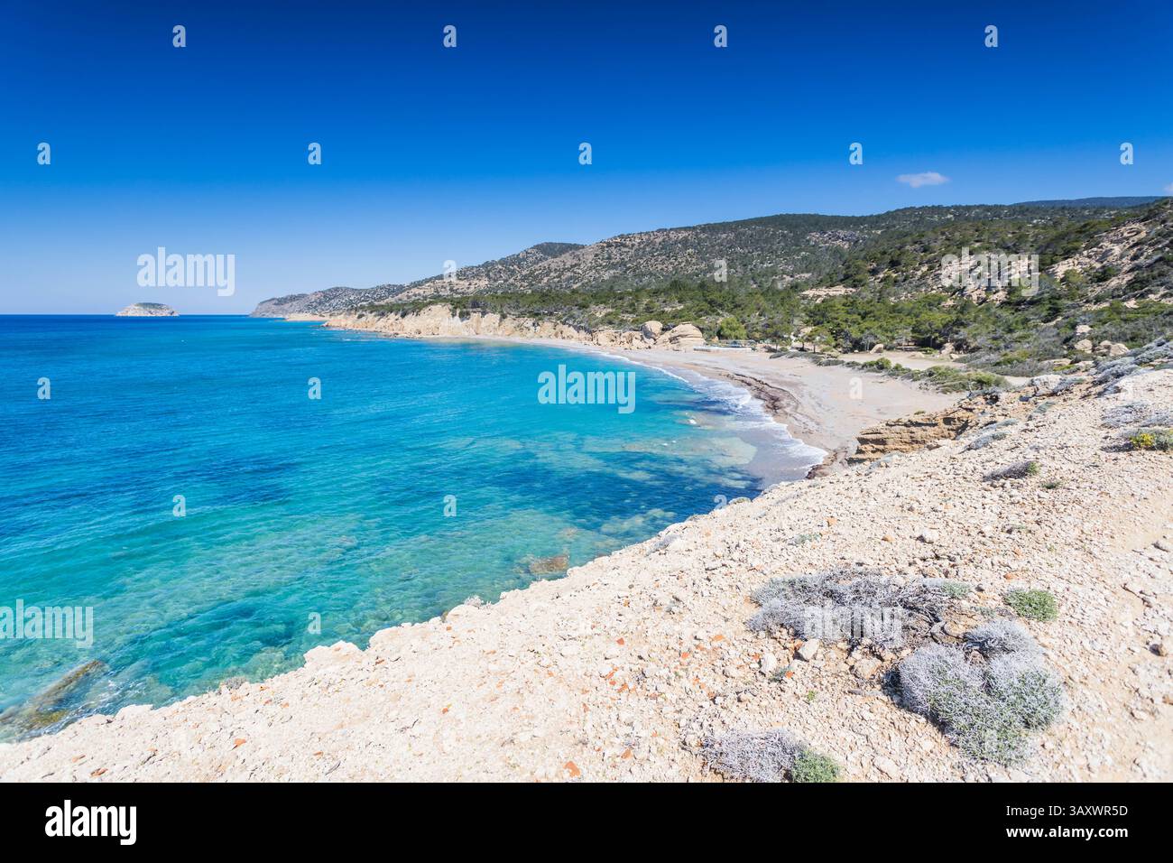 A sweeping view of the blue sea meeting the sand, pebbles and rocks ...