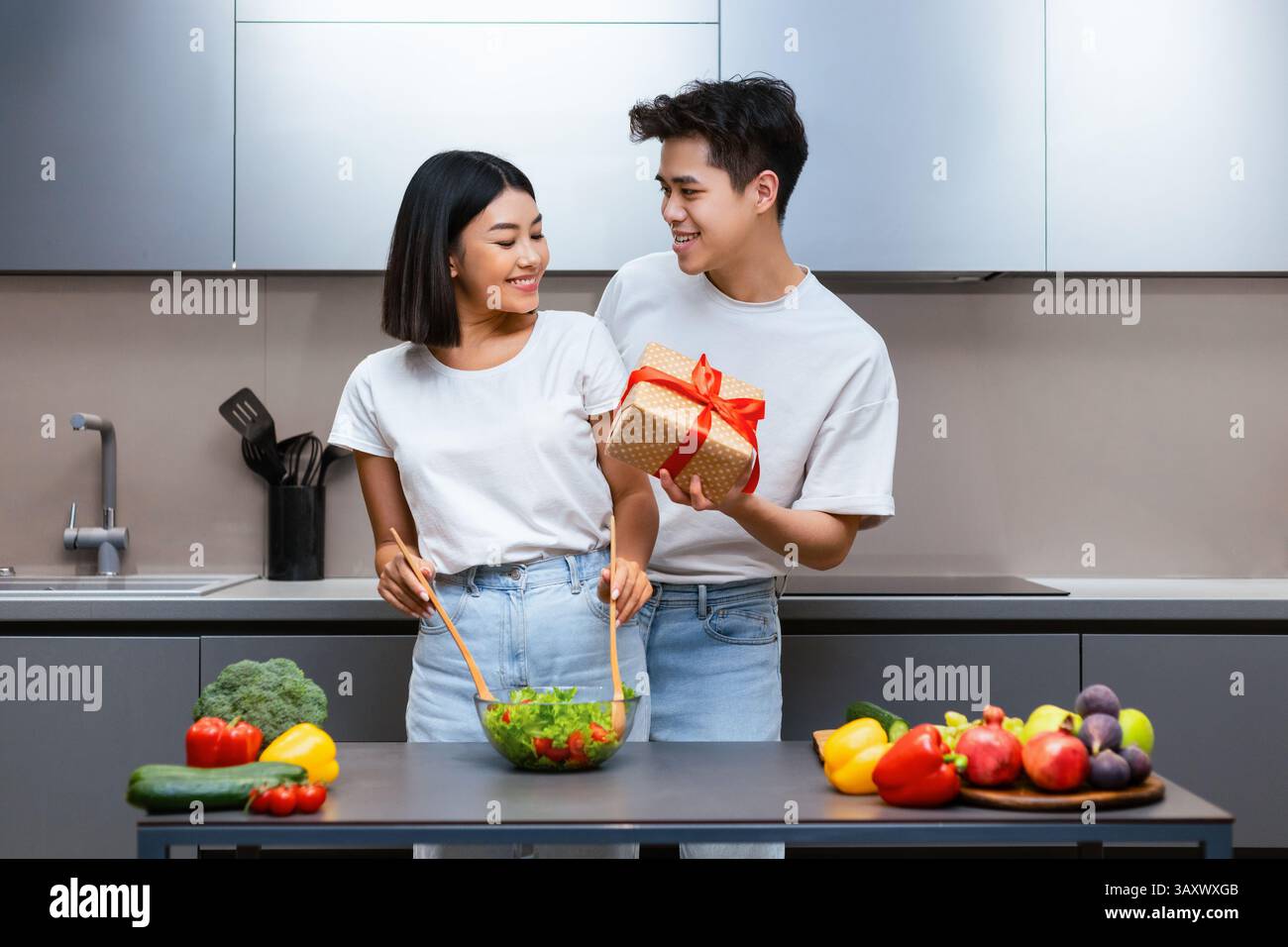 Husband Giving Wrapped Present To Happy Wife In Modern Kitchen Stock ...