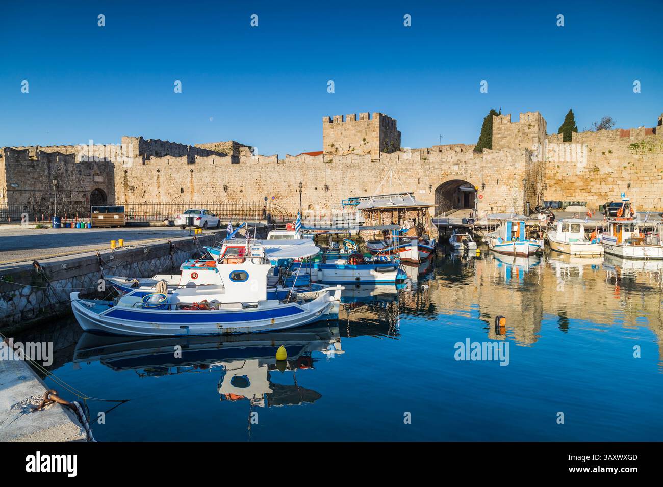 Fishing boats in Rhodes harbour lit up by the early morning golden ...