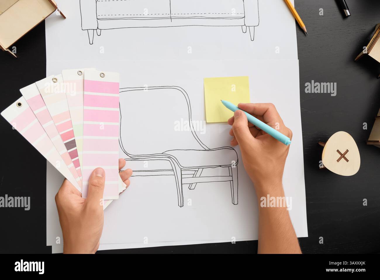 Male furniture designer with color palettes working on black table, top ...