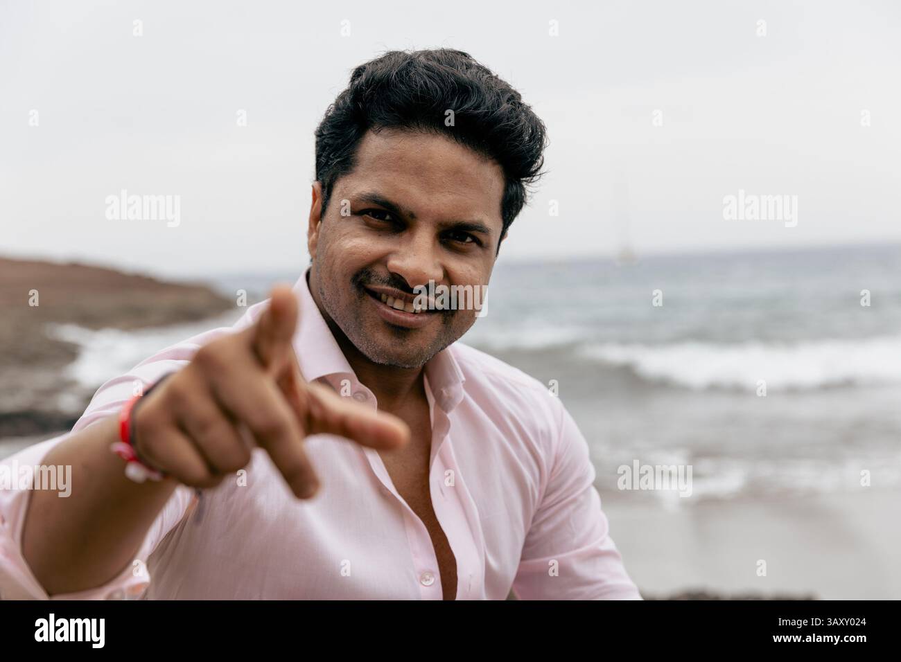 A smiling and confident Indian man pointing towards the camera while at ...