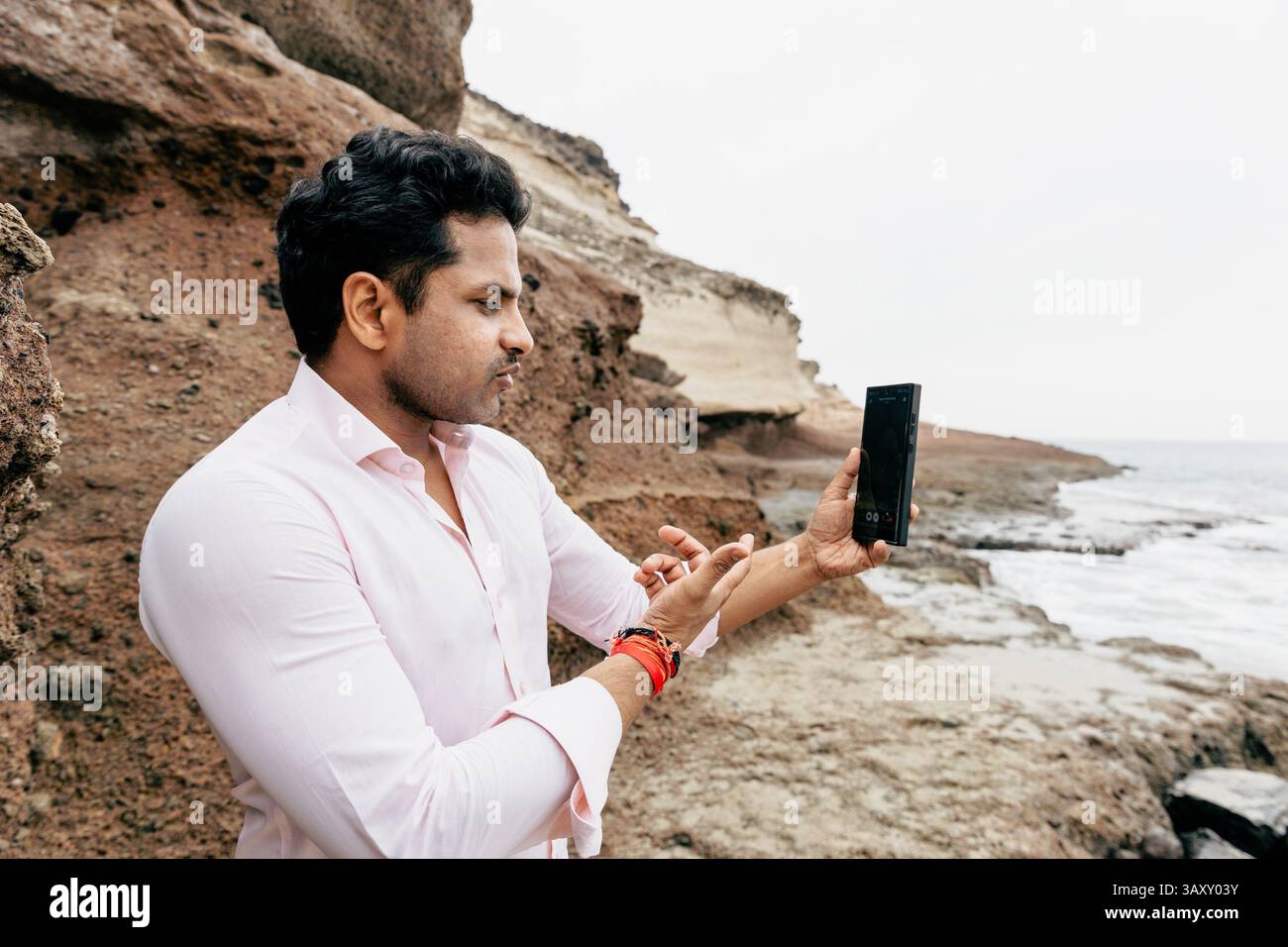 A man is having a conversation through a video call at the beach while ...