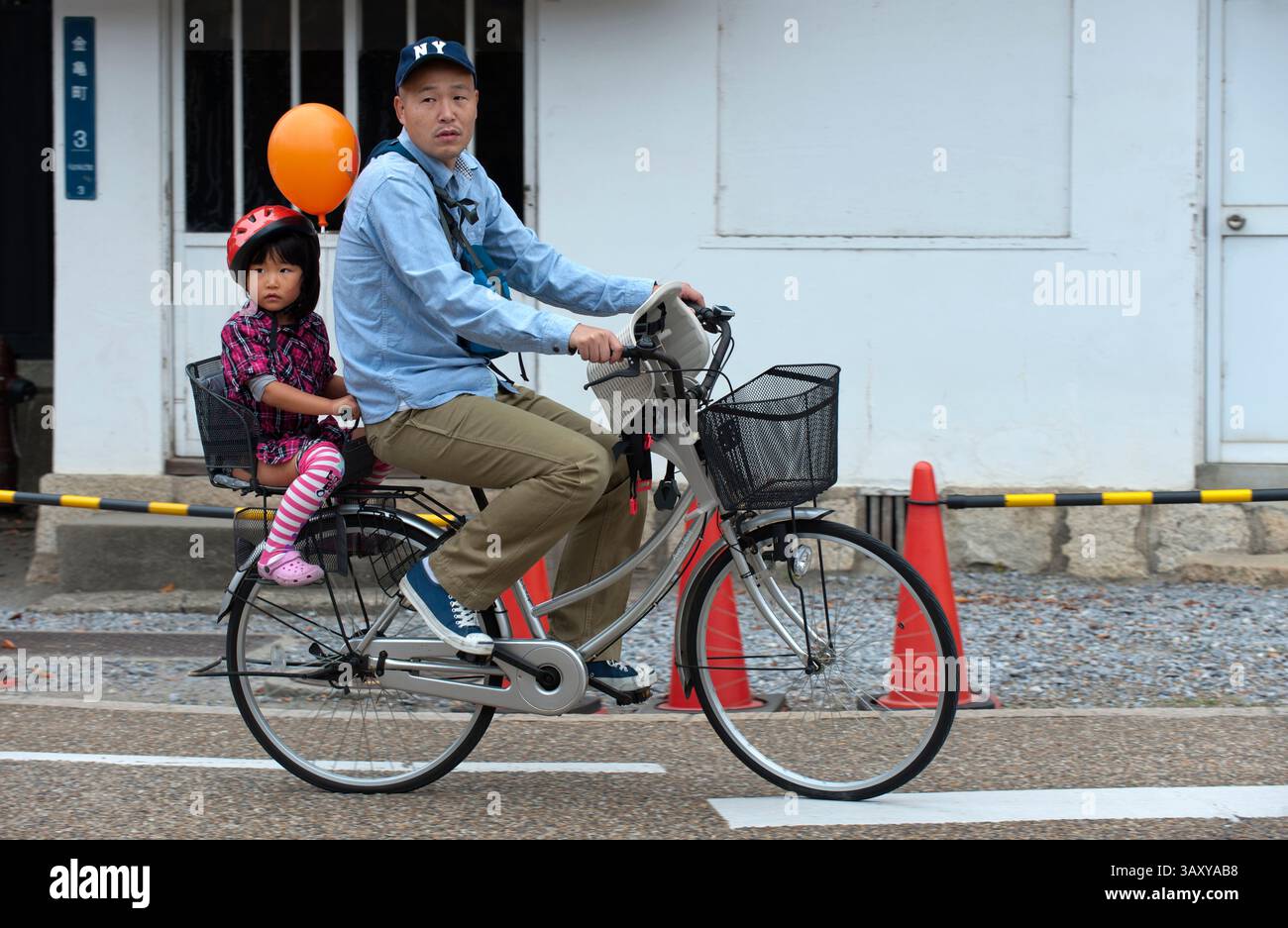 Father riding on a bicycle with daughter aboard in a special rear seat ...