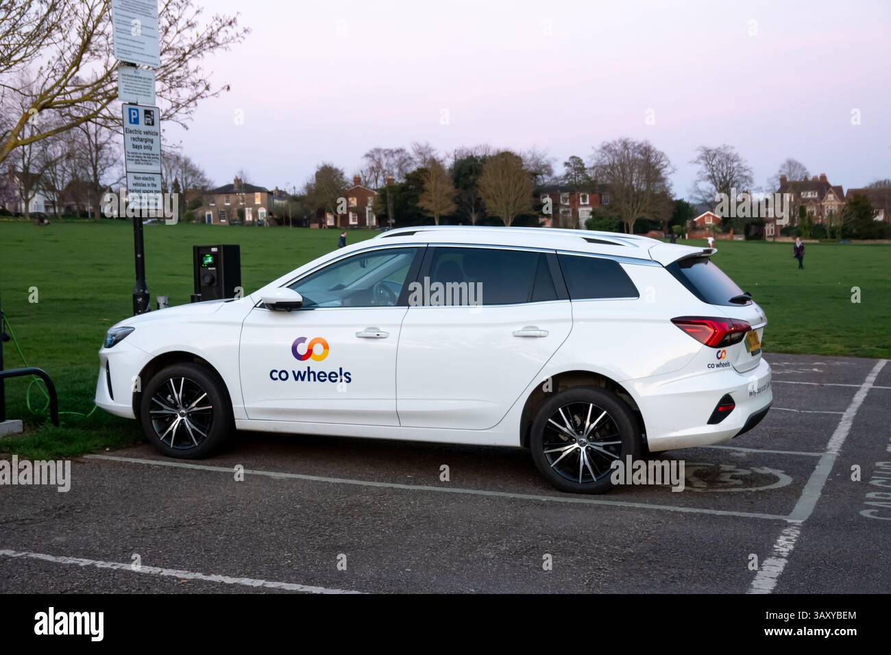 A white Co Wheels electric car, EV, parked near a charging station in ...