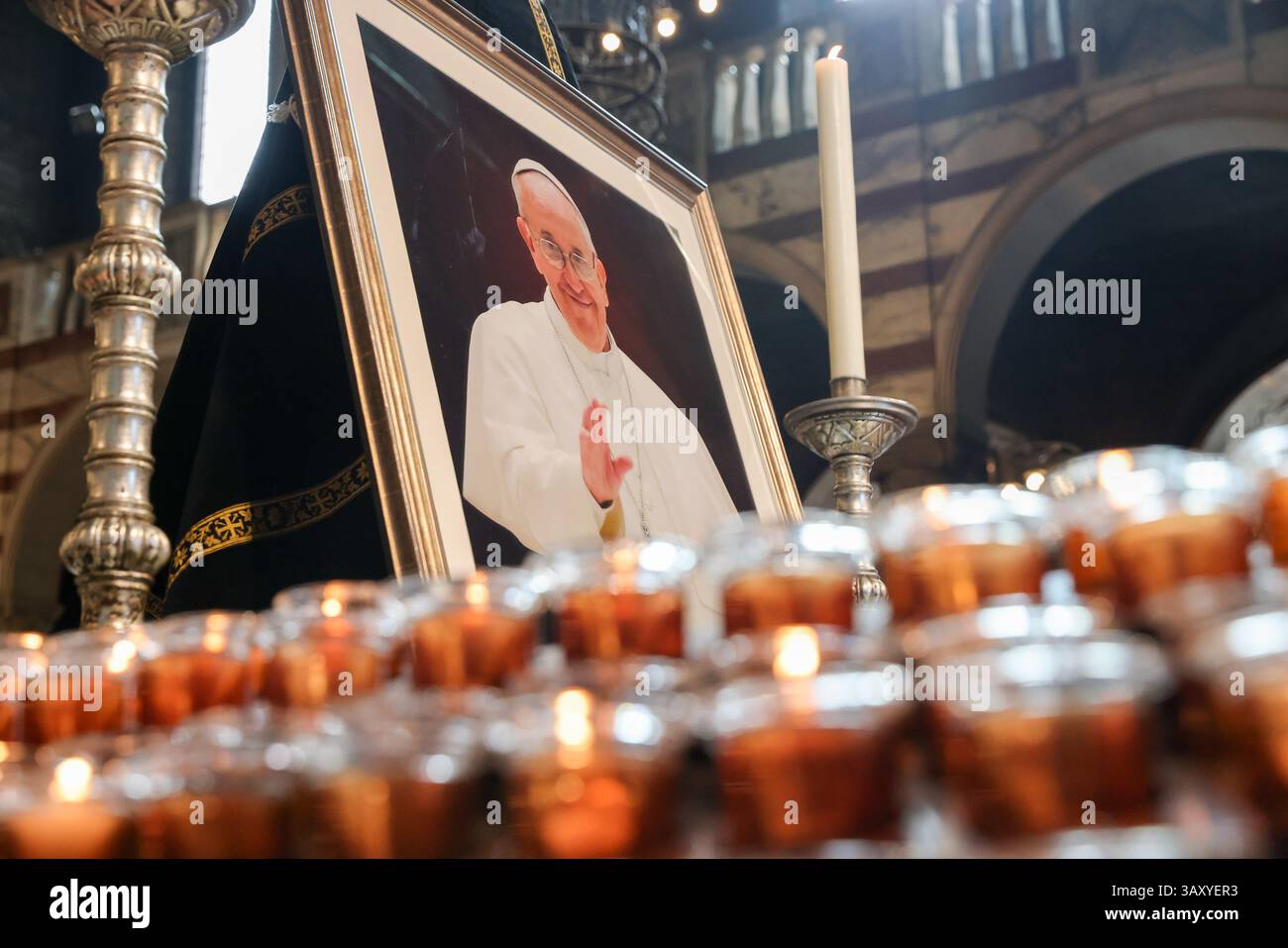 London, UK. 21st Apr, 2025. Candles surround an image of the Pope in ...