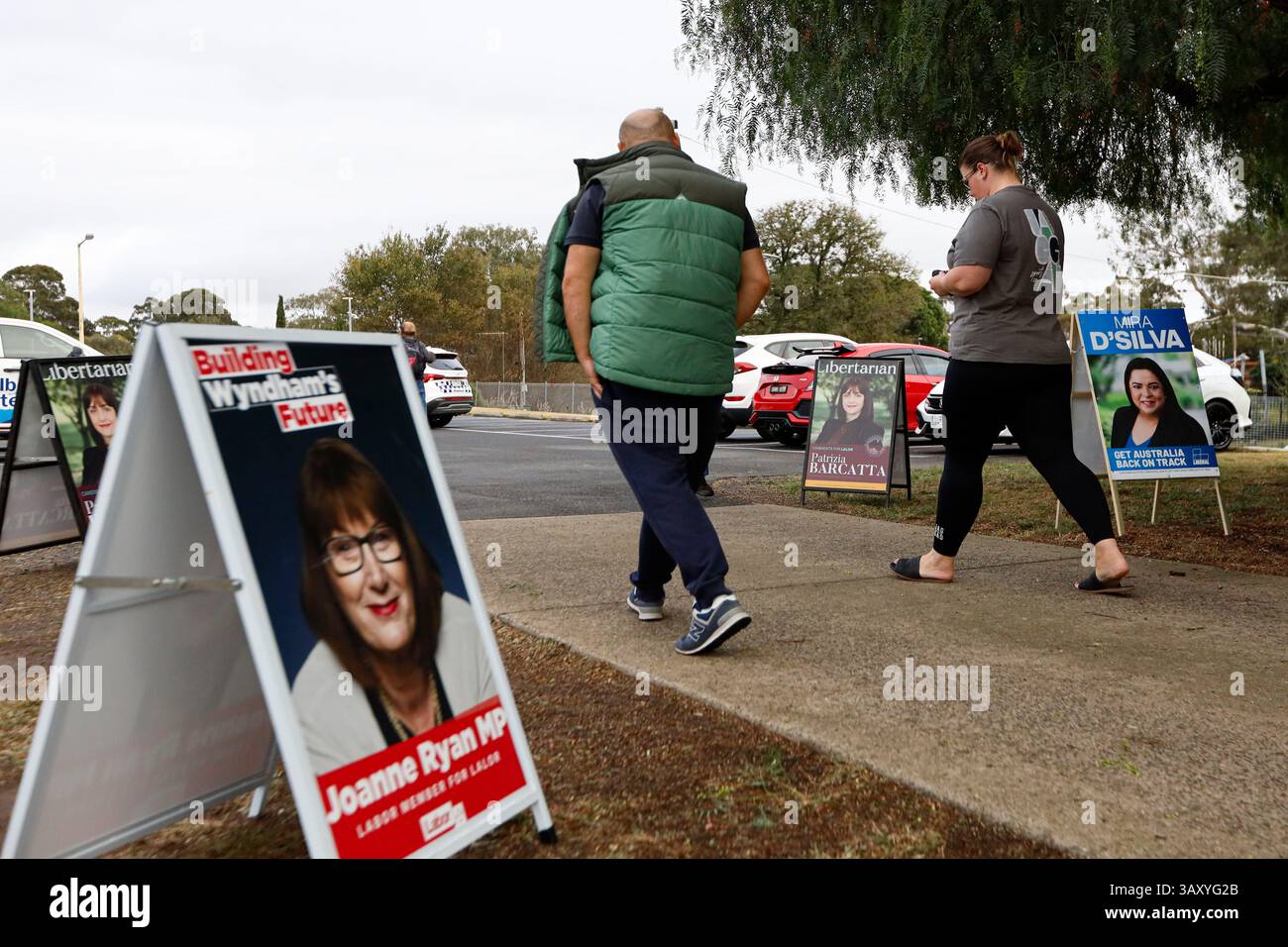 Melbourne, Australia. 22 April, 2025. Voters walk past campaign posters ...