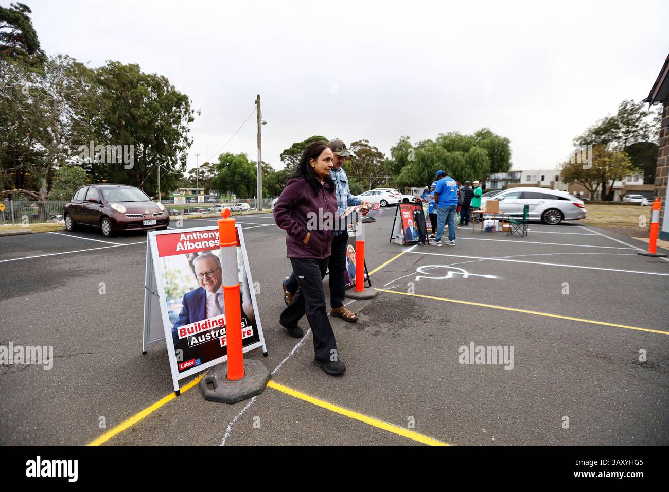 Voters walk past campaign posters inside a polling centre during early ...