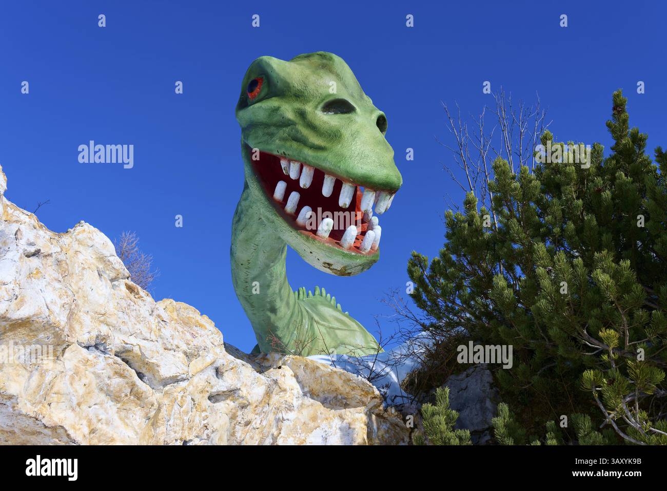 Green dinosaur sculpture, Diplodocus, in front of a blue sky with ...