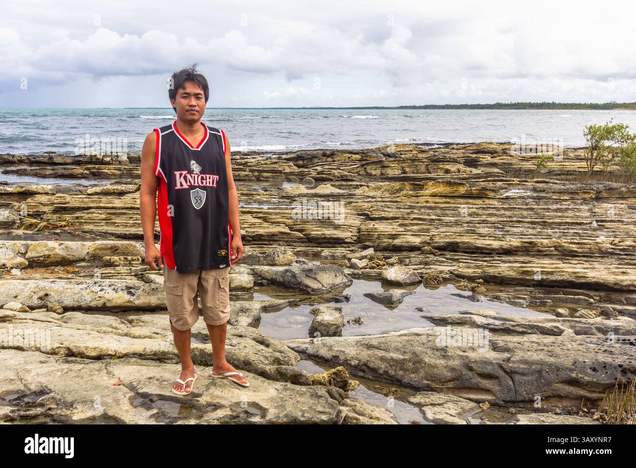 A Filipino man stands at the Afga Wave Rock Formation in Tangalan ...
