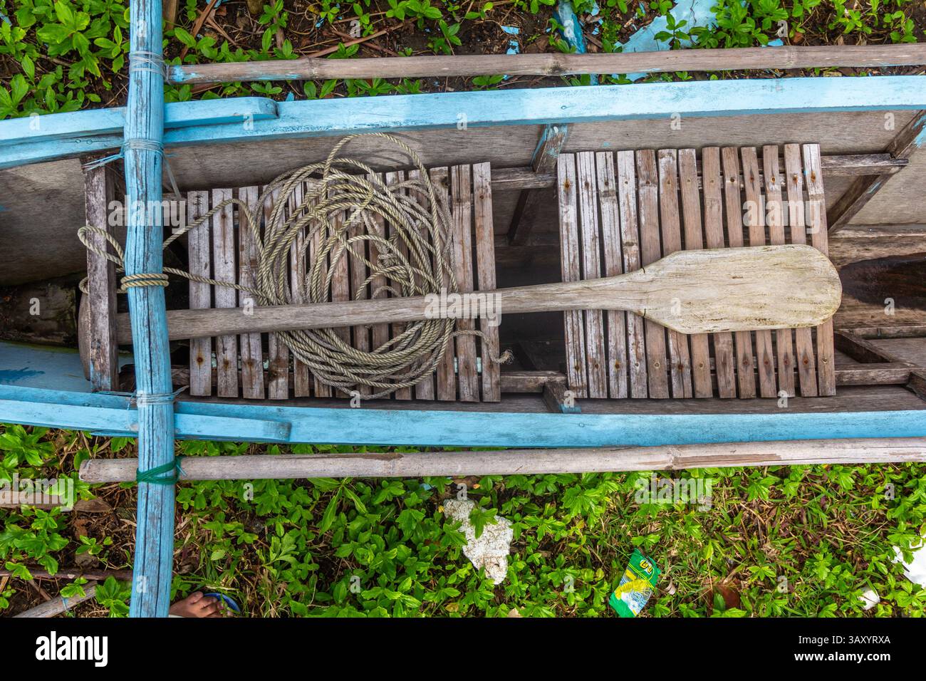 A wooden oar rests on a banca beside coastal weeds in Aklan ...