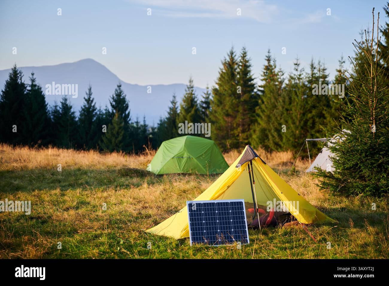 Solar panel in grassy field with tents in background highlights eco ...