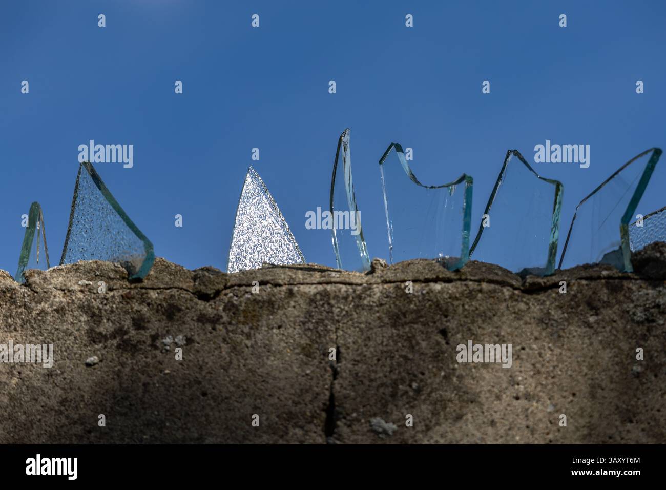 Concrete fence with pieces of glass, protection against thieves, broken ...