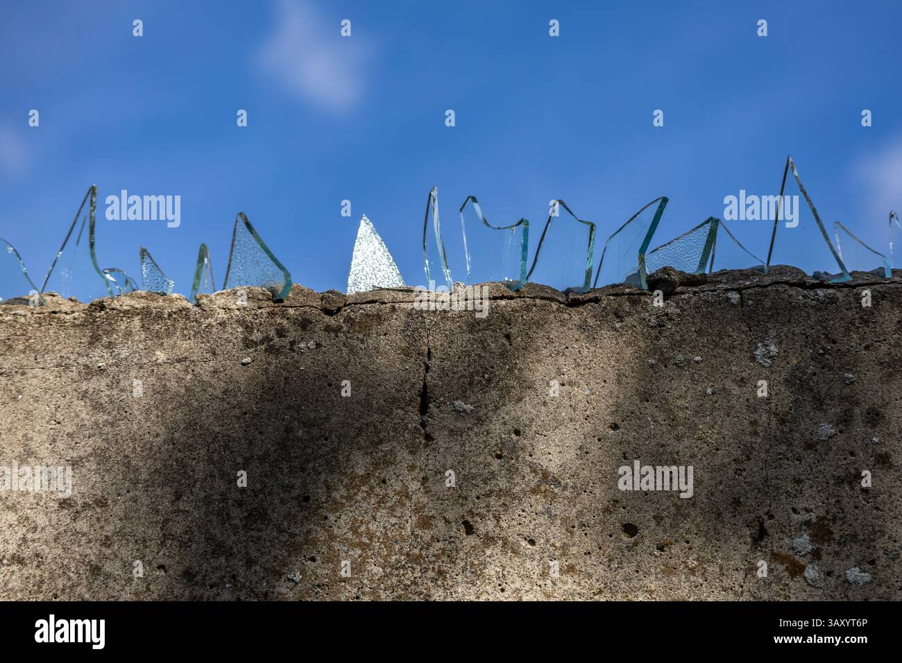 Concrete fence with pieces of glass, protection against thieves, broken ...