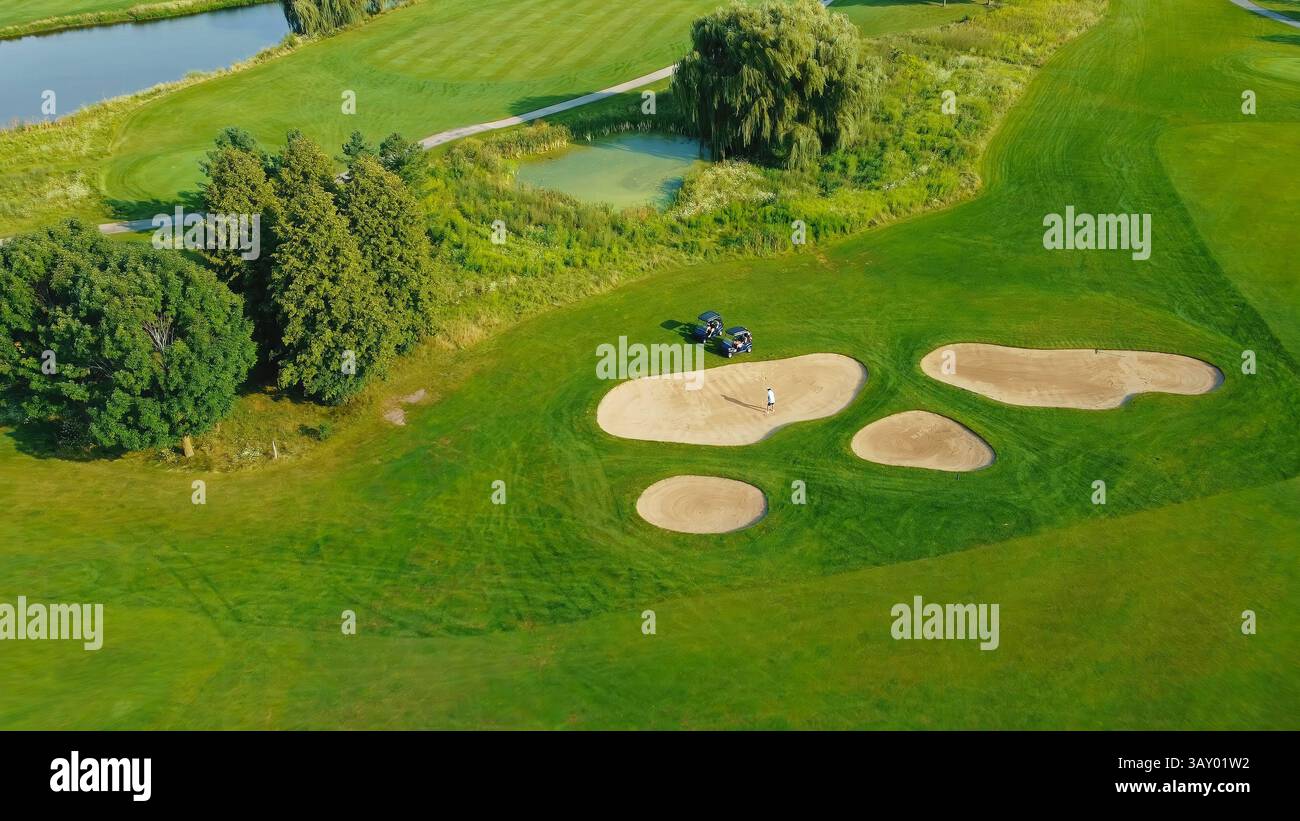 Aerial view of a golf course with sand bunkers and golf cart. A vibrant ...