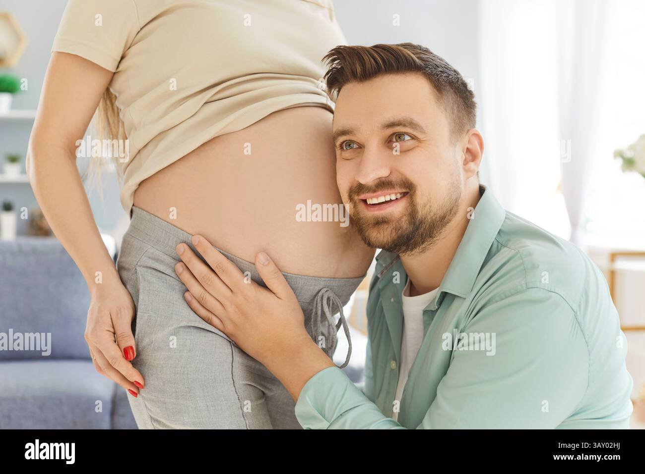 Happy smiling excited expectant father cuddling his wife pregnant belly ...