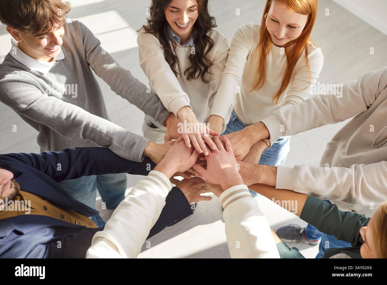 Group of people stacking hands, involved in teambuilding activity, gesturing after goal ...
