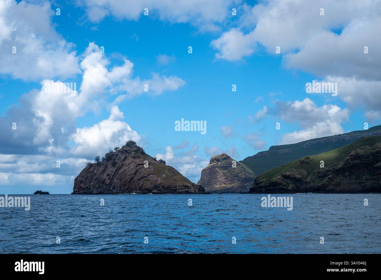 Green cliffs rise above the ocean along the rugged coastline between ...