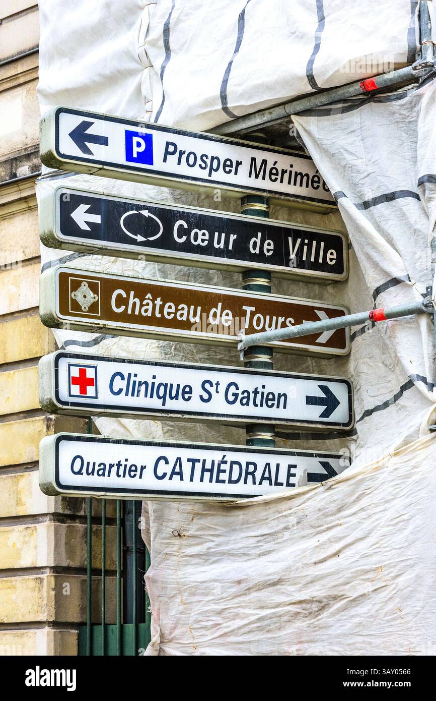 Road direction signs poking out from building covered in scaffolding ...
