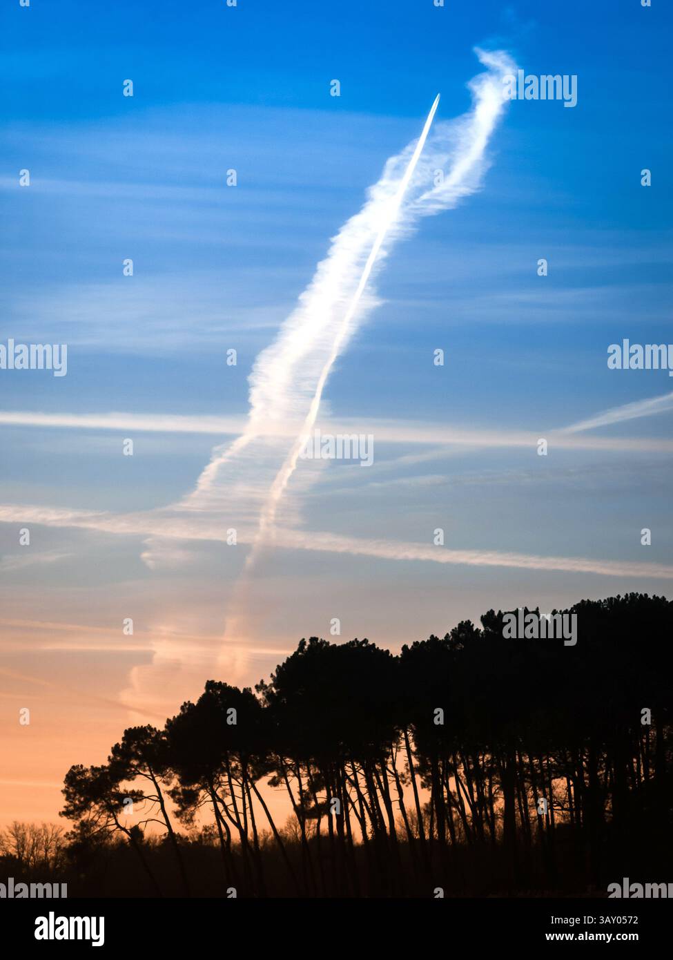 Jet airplane contrails crossing in different directions, one blown by ...
