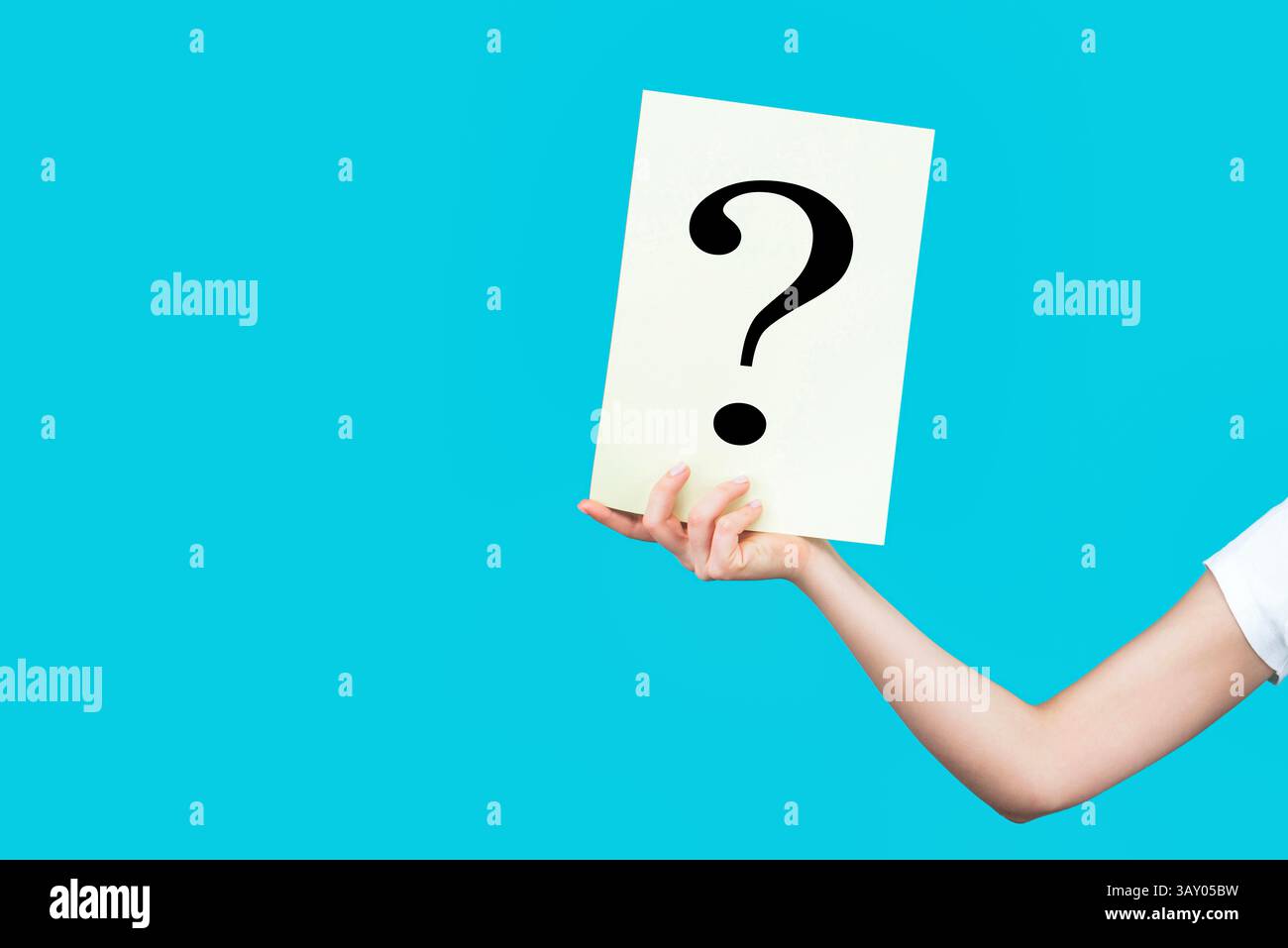 Hand holding a white question mark paper against a blue background ...