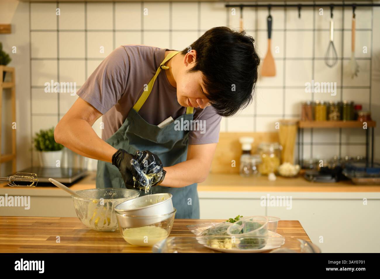Man squeezing freshly churned butter, separating buttermilk into bowl ...
