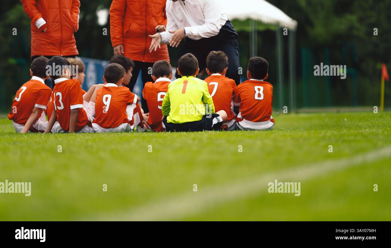 A youth soccer team listens attentively to their coach during a team ...