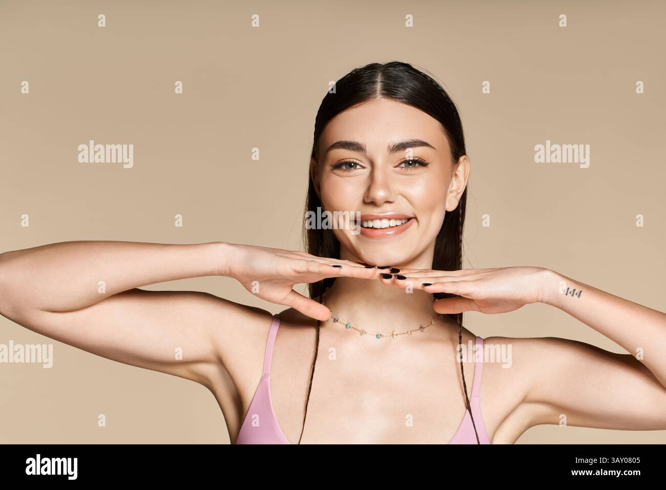 A young woman with a beautiful sun tan smiles joyfully while embracing ...