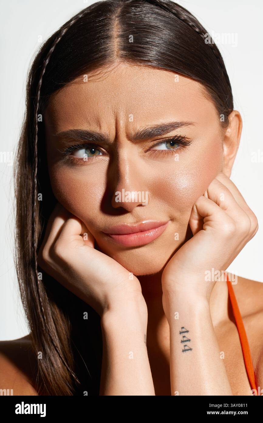 Young woman with a sun tan reflects on summertime while playfully ...
