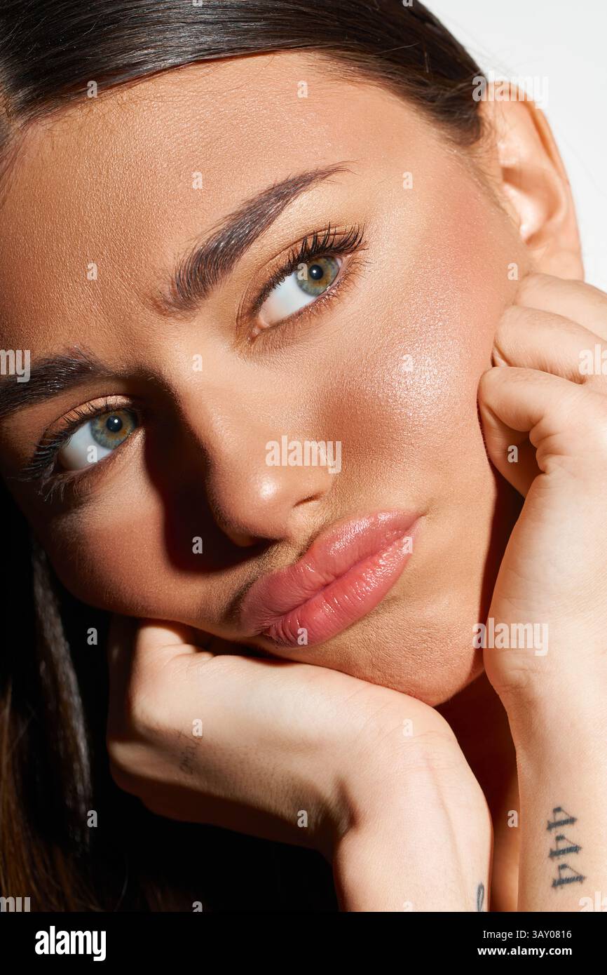 A young woman highlights her sun-kissed skin while playfully posing ...