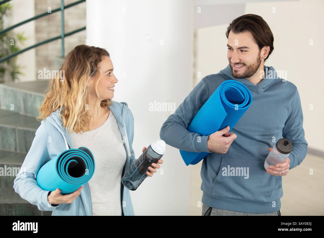 fit couple holding water bottle and exercise mat Stock Photo - Alamy