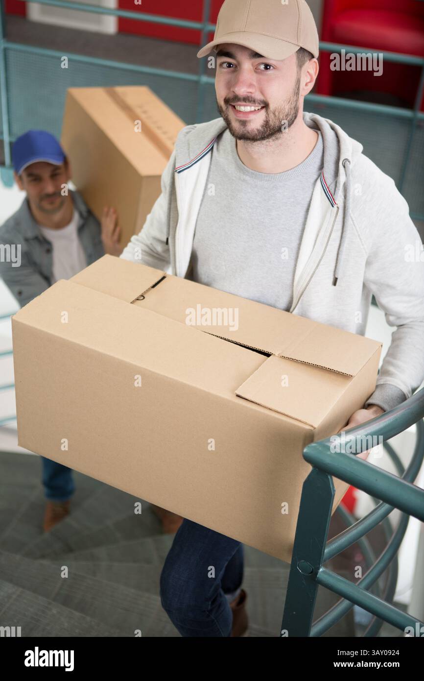 two men carrying boxes up a flight of stairs Stock Photo - Alamy