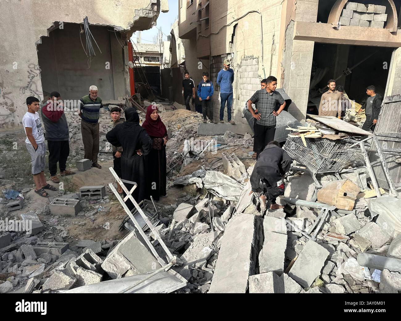 Palestinians inspect the area among the rubbles of destroyed buildings ...