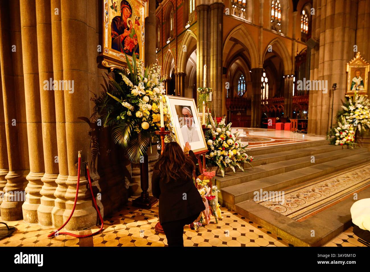 A woman prays while holding a photograph of Pope Francis during a ...