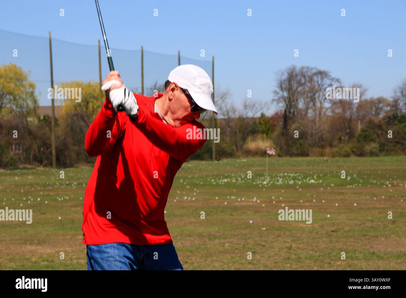 Golf player practices swings under clear skies at a driving range with ...