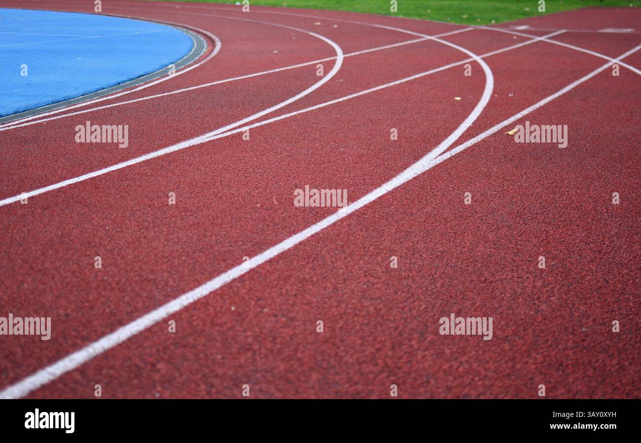 red running track curve with white lines, blue sports field in left ...