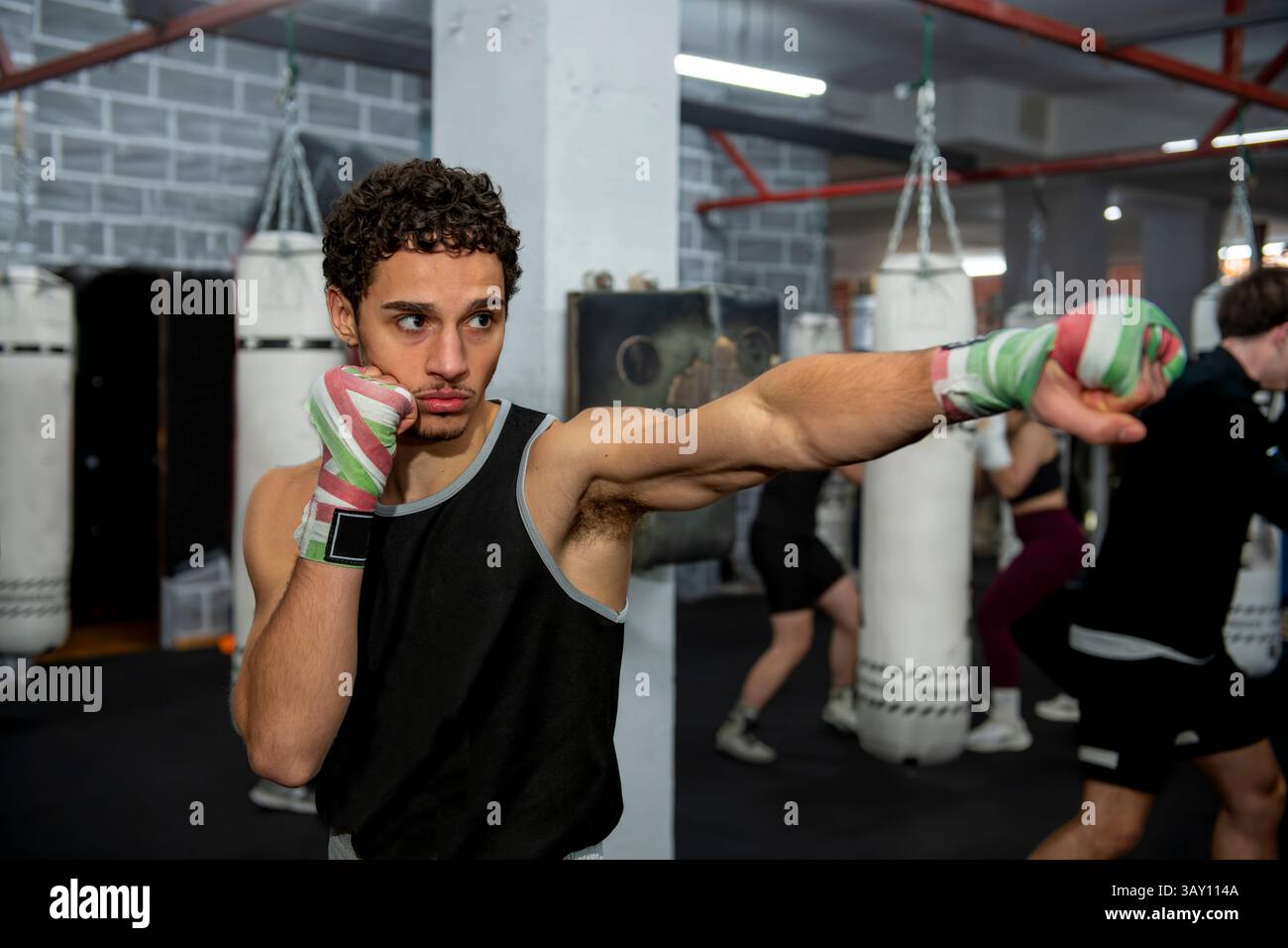 Young boxer practicing punches with hand wraps in a boxing gym ...
