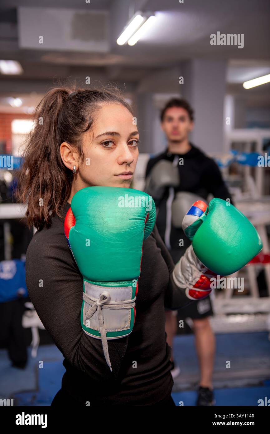 Determined female boxer wearing green boxing gloves posing confidently ...