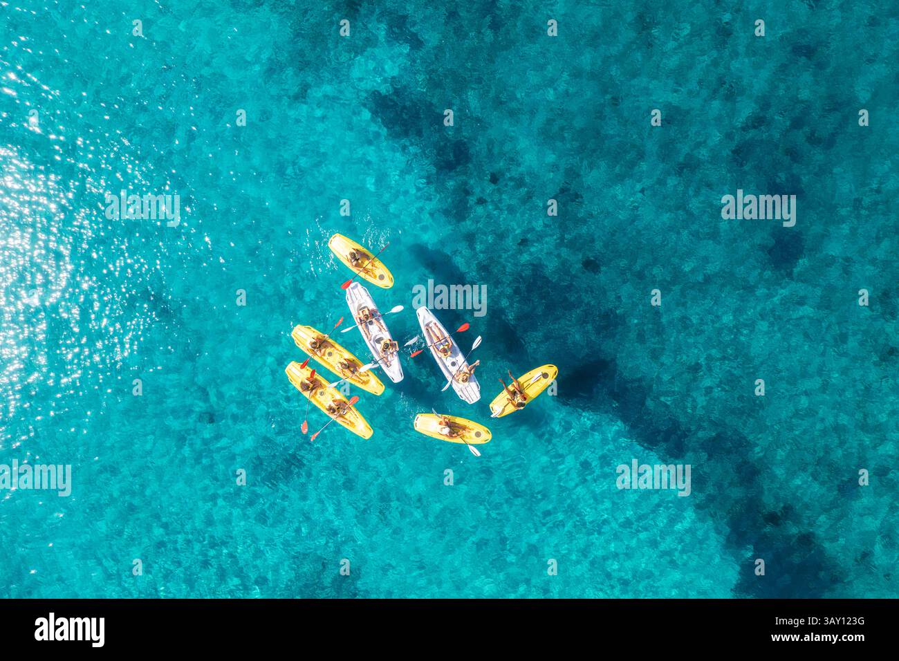 Aerial view of yellow kayaks in blue sea at sunset in summer. People on ...