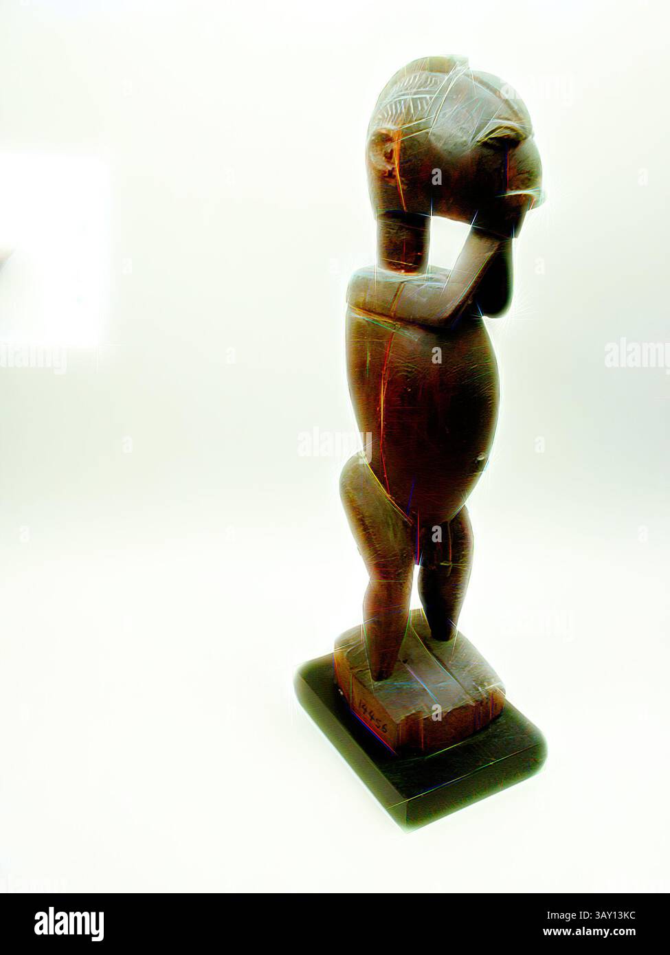 A intricately carved wooden figure stands in a thoughtful pose ...