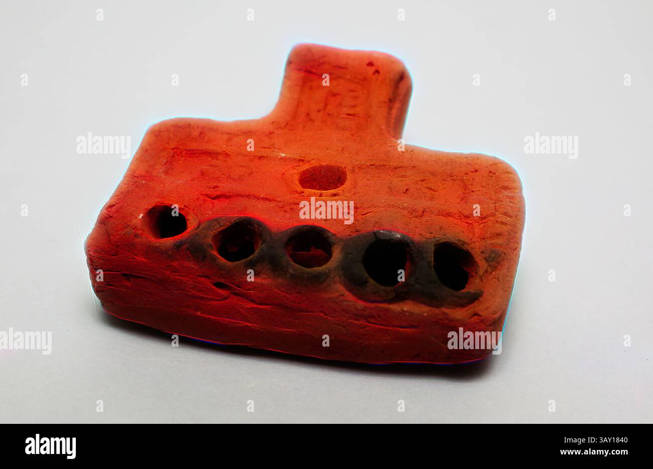 An intricately carved artifact featuring five circular openings, its ...